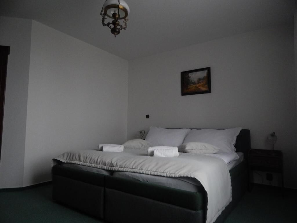 Quarto com cama, mesa de cabeceira, abajur e pintura na parede.