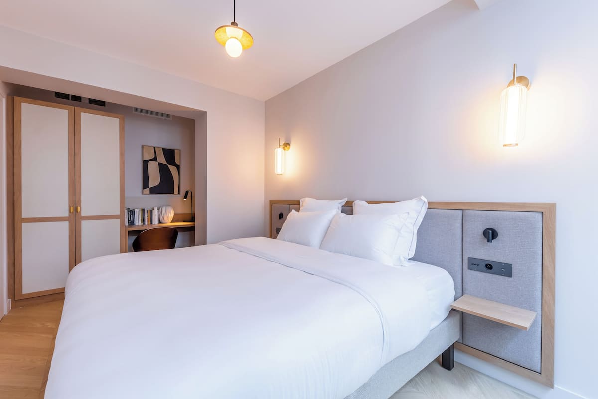 Um quarto moderno com uma cama grande, mesas de cabeceira e luminárias fixadas na parede.