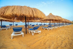 Na praia, praia de areia branca, espreguiçadeiras, guarda-sóis de praia 