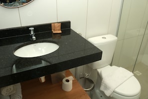 Casa de banho com lavatório de bancada preta, sanita e rolo de papel higiénico.