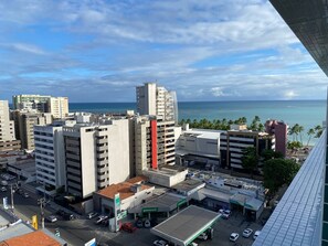 Paisagem urbana com vista para o oceano, apresentando edifícios modernos, um estacionamento e um posto de combustível.