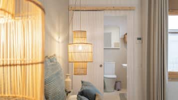 Quarto com cama, luminária de cabeceira e luminária pendente.