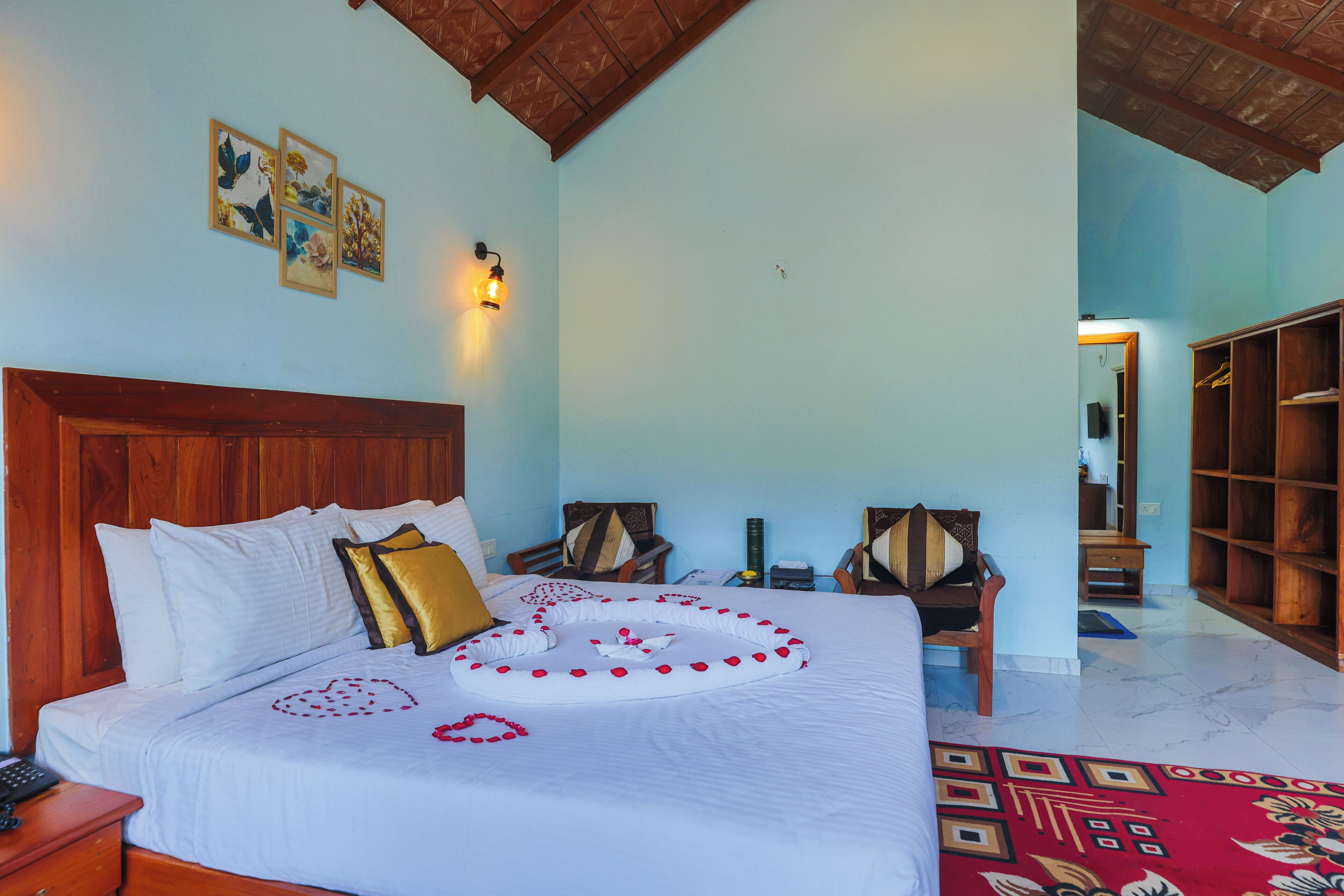Cama bem arrumada com decoração em formato de coração, cabeceira de madeira e mesa de cabeceira pequena com abajur.