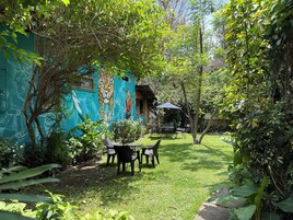 Um jardim com um mural, uma mesa com cadeiras e um espaço de estar coberto.