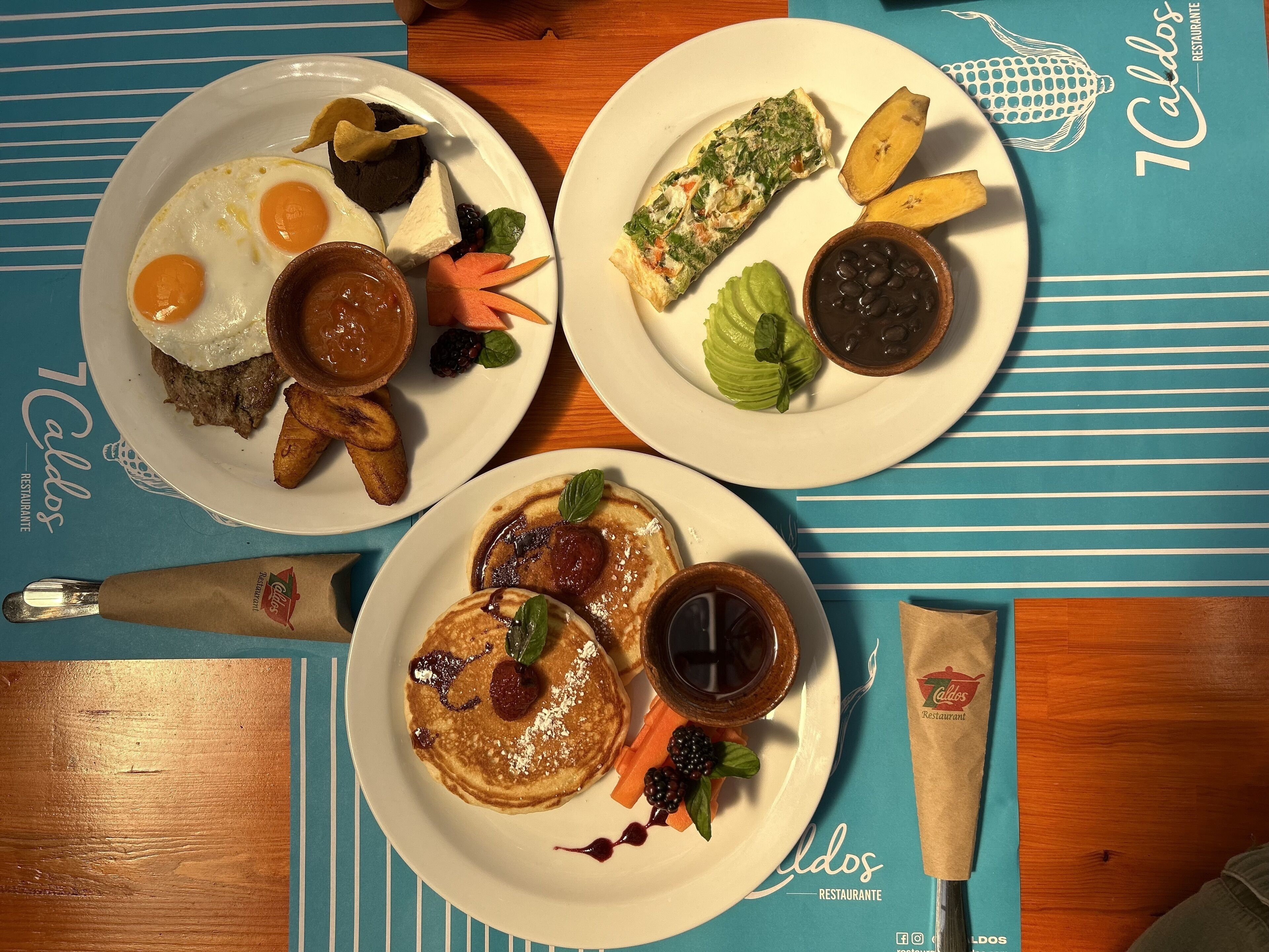 Três pratos de comida sobre uma mesa com um jogo americano azul.