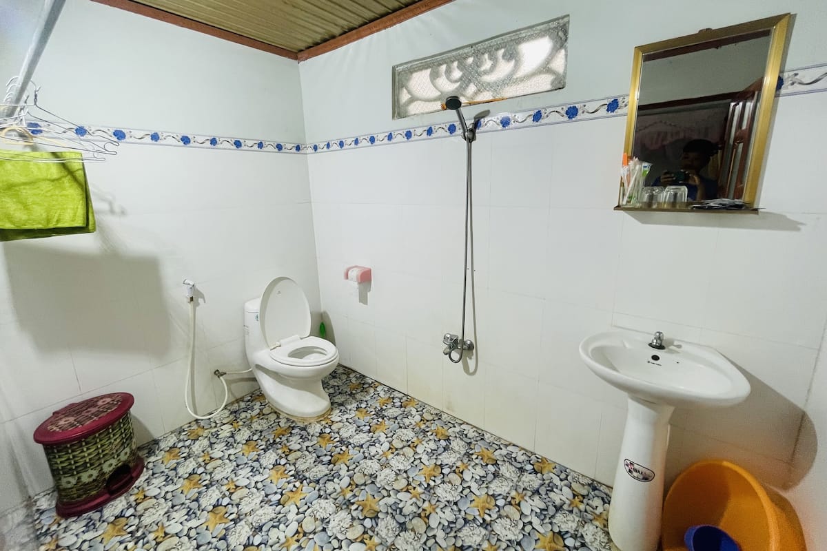 Um chuveiro fixo, um secador de cabelo, roupões, chinelos