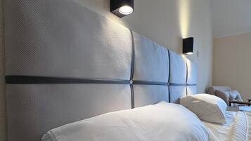 Quarto de hotel moderno com uma cama grande, cabeceira com design texturizado e duas luminárias fixadas na parede.