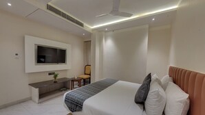 Quarto de hotel moderno com cama, televisão, escrivaninha e cadeira.