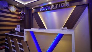Uma área de recepção com design moderno, incluindo um balcão de atendimento, um relógio e uma placa com a inscrição "RECEPTION".