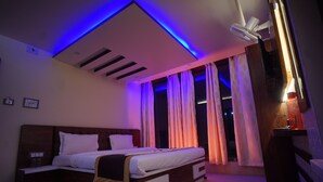 Um quarto moderno com uma cama, um ventilador de teto e uma mesinha de cabeceira.