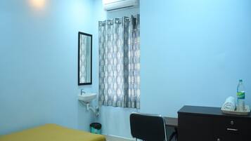 Quarto com cama, escrivaninha, cadeira, pia e ar condicionado.