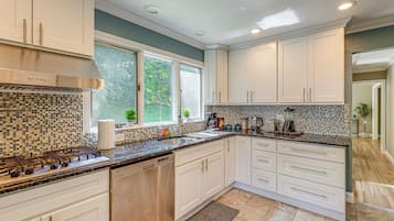 Uma cozinha moderna com armários brancos, painel de azulejos e eletrodomésticos de aço inoxidável.