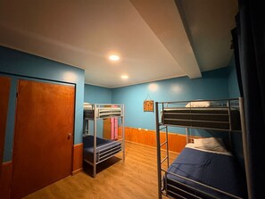 Quarto com beliches, porta de madeira e um pequeno objeto decorativo na parede.