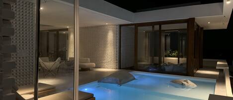 Uma área de spa moderna com hidromassagem, assentos e um chuveiro em compartimento de vidro.