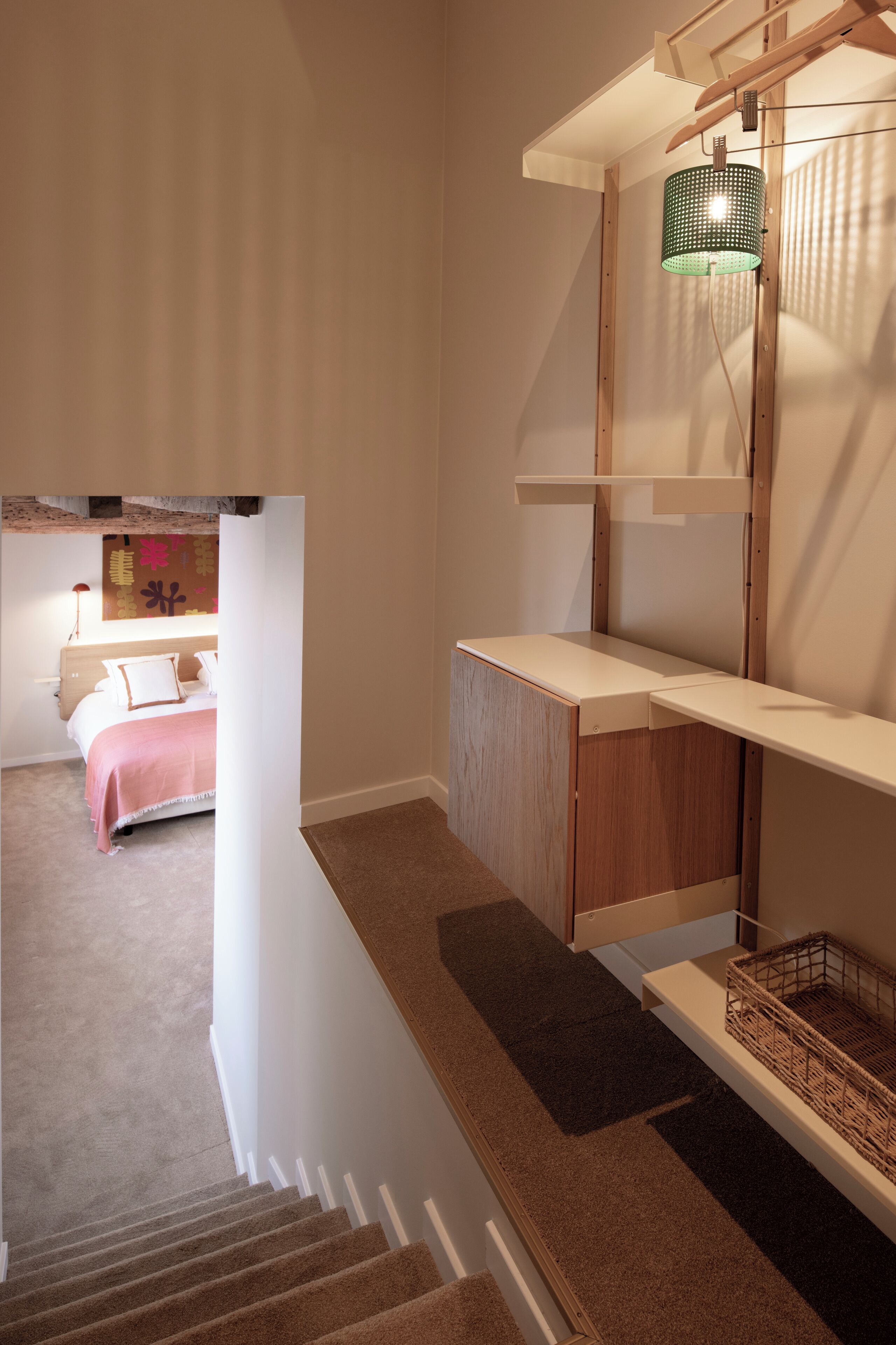 Um interior moderno com escada, cama, escrivaninha e luminária suspensa.