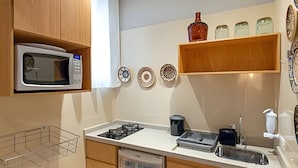 Uma cozinha com micro-ondas, fogão, pia e pratos decorativos.
