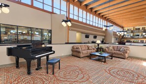 Um hall amplo com um piano de cauda, assentos confortáveis e um tapete estampado.