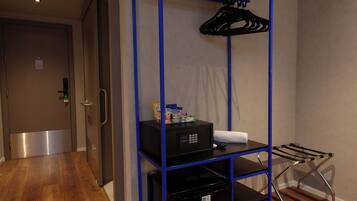 Quarto compacto com uma estante de metal azul, micro-ondas e uma pequena mesa.