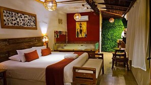 Quarto com cama grande, mesa pequena, cadeira e parede verde.