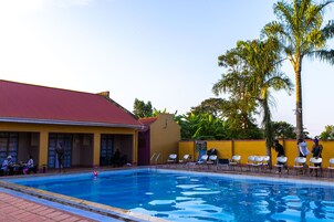Piscina com espreguiçadeiras e um edifício com telhado vermelho.