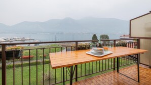 Uma mesa de madeira numa varanda com vista para um lago e montanhas.