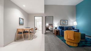 Uma sala de estar moderna com uma parede azul de destaque, uma poltrona amarela e uma área de jantar com mobiliário de madeira.