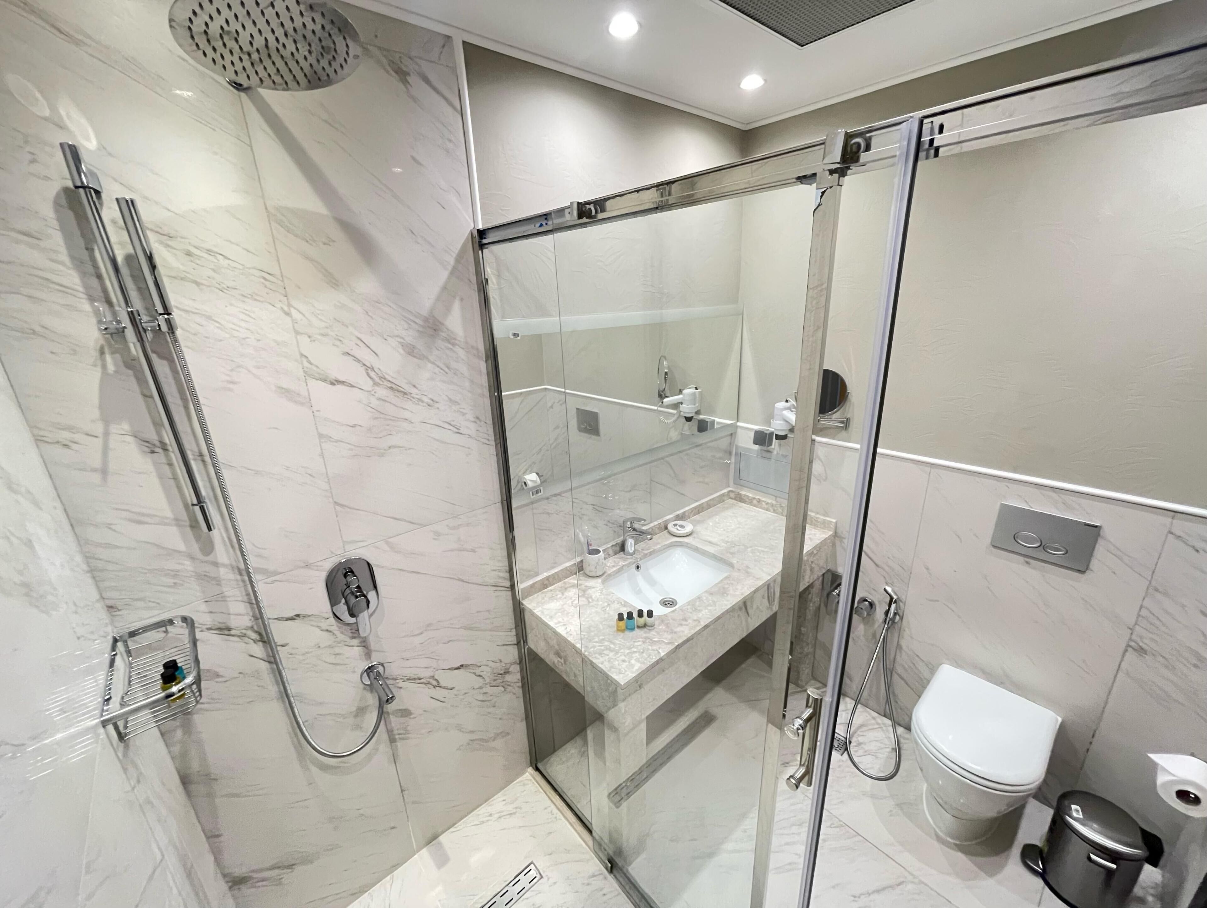 Uma casa de banho moderna com chuveiro em cabine de vidro, lavatório e sanita.