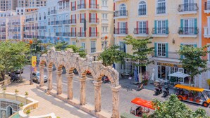 Uma rua histórica com edifícios coloridos, um café e um carro antigo.