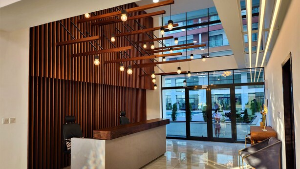 Uma área de recepção moderna com uma parede de ripas de madeira, um balcão de atendimento e uma porta de vidro que dá para o exterior.