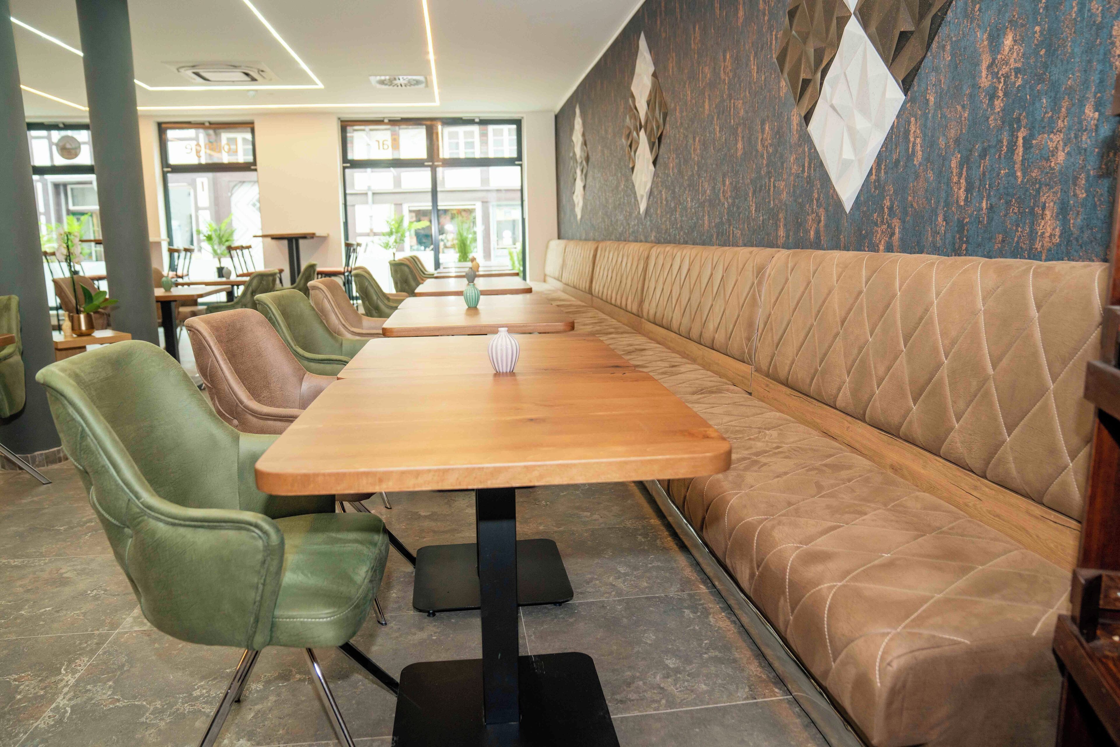 Um restaurante com uma longa mesa de madeira e assentos acolchoados.