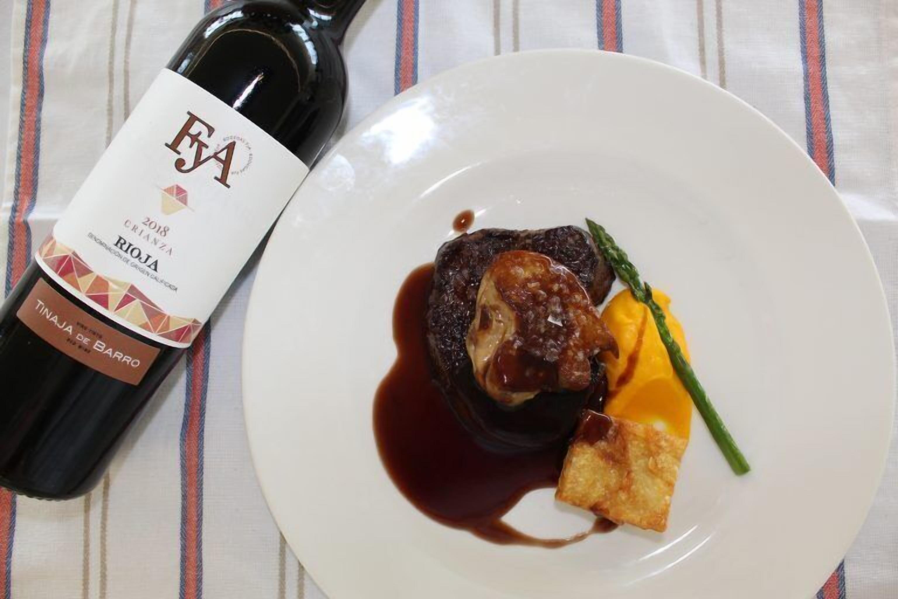 Uma garrafa de vinho e um prato com um bife.