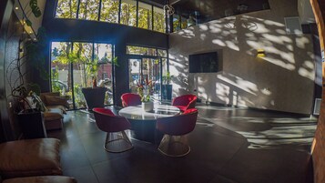 Um interior moderno com uma mesa redonda, cadeiras vermelhas e plantas em vasos.