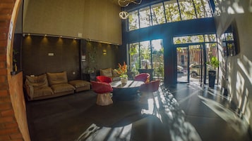 Um interior moderno com um sofá, cadeiras vermelhas, uma mesa e um vaso com planta.