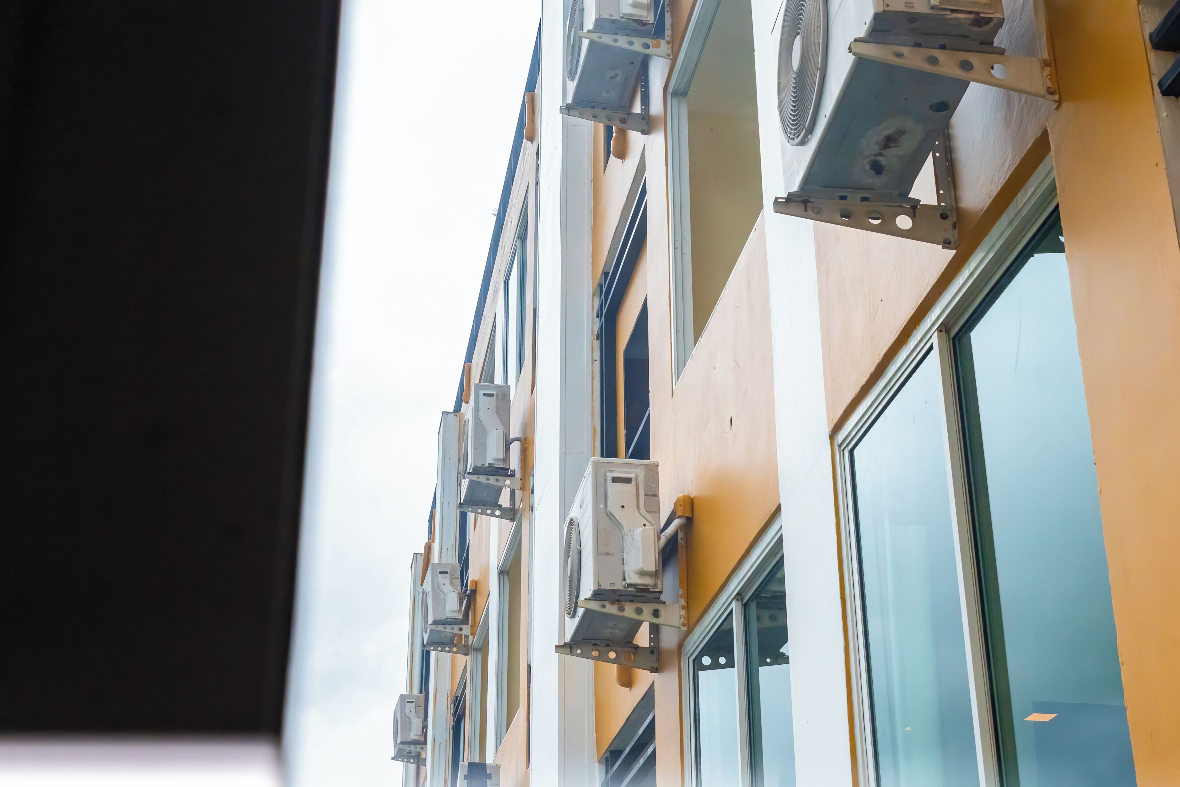 Fachada de edifício com vários aparelhos de ar condicionado fixados na parede externa.