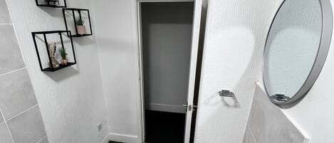 Um banheiro moderno com banheira, pia e três prateleiras fixadas na parede com objetos decorativos.
