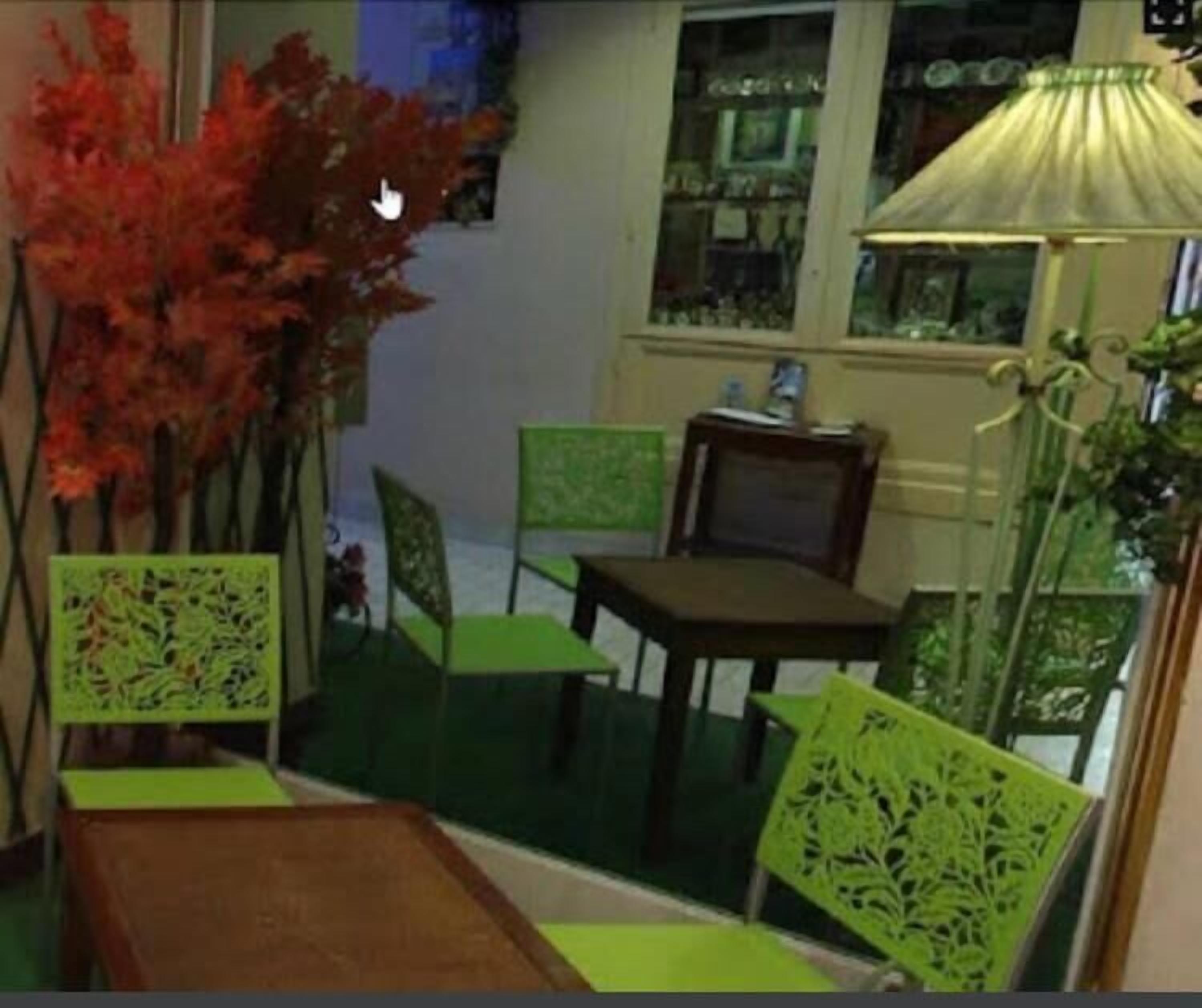 Uma sala de jantar com uma mesa e cadeiras, uma luminária e um vaso com flores vermelhas.