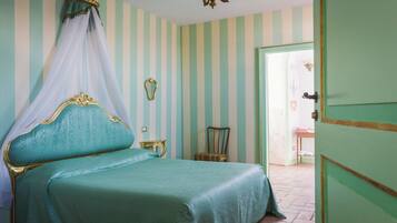 Um quarto com cama, cadeira, mesa e porta.