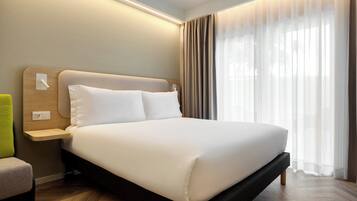 Quarto de hotel moderno com uma cama grande, uma mesa de cabeceira e uma cadeira.