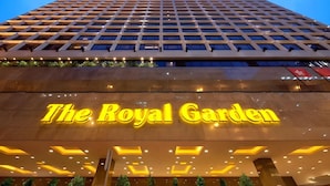 Fachada do hotel Royal Garden, com grade de janelas e um letreiro iluminado em destaque.