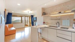 Cozinha moderna com uma ilha grande, área de refeições com sofá e vista para o exterior.