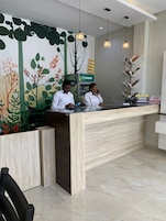 Uma receção com design moderno, uma máquina de café e um mural na parede.