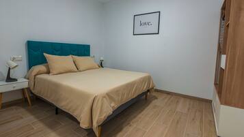 Quarto com cama, mesa de cabeceira, luminária e um quadro pendurado na parede.