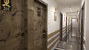 Corredor de hotel com paredes de mármore, portas numeradas 201 e 212, e chão preto polido.