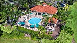 Vista aérea de um resort com piscina, espreguiçadeiras e palmeiras.