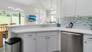 Uma cozinha moderna com armários brancos, lava-louças em aço inoxidável e painel de azulejos.