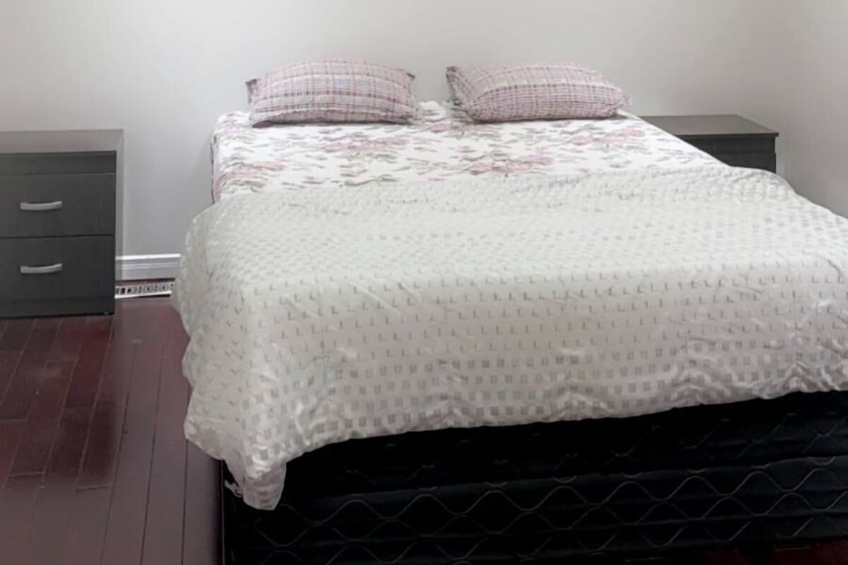 Quarto com cama, ventoinha no teto e mesa de cabeceira.