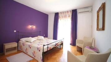 Quarto com cama, mesa de cabeceira, cadeira e aparelho de ar condicionado.