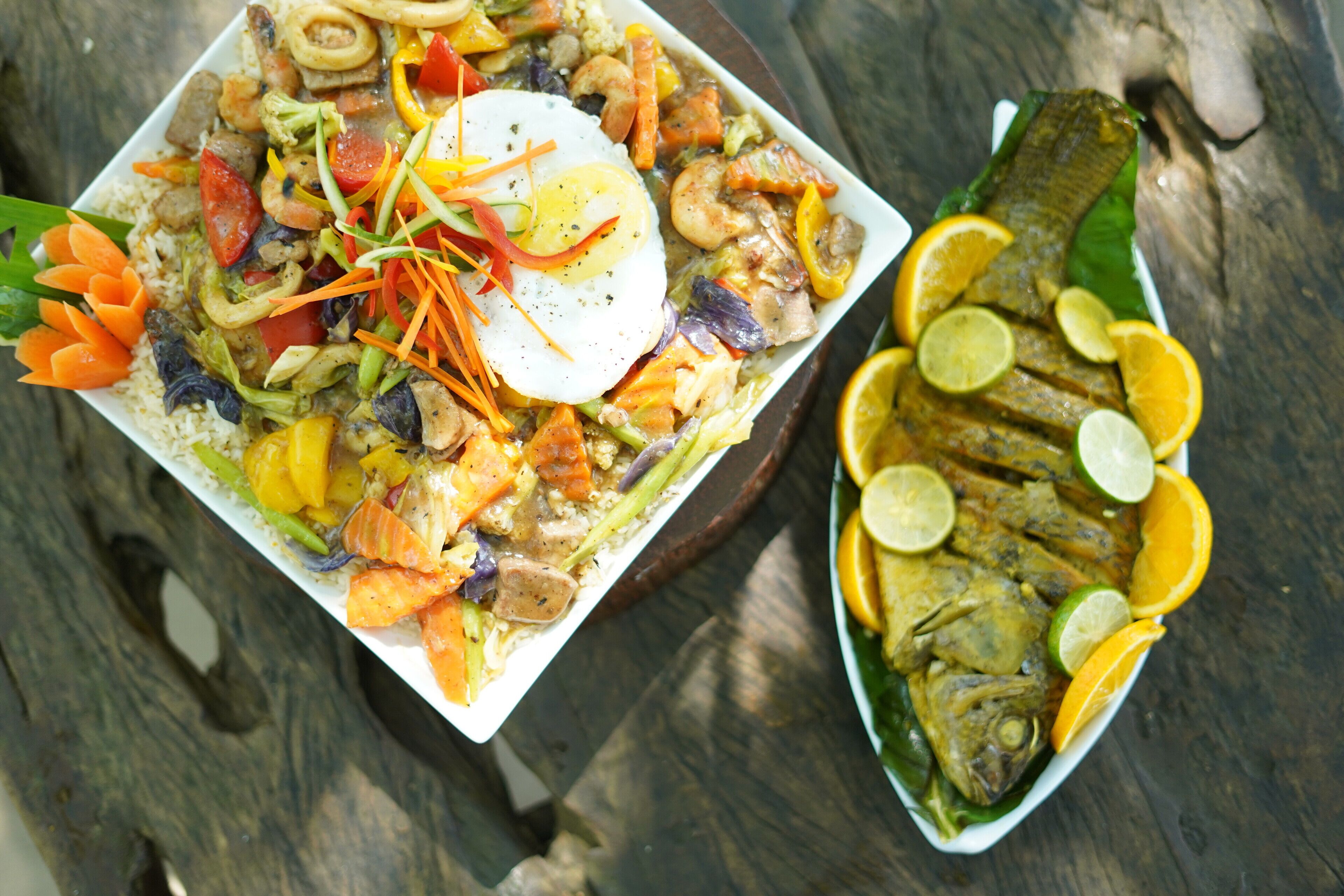Uma refeição com diversos vegetais, peixe e um ovo escaldado em um prato.