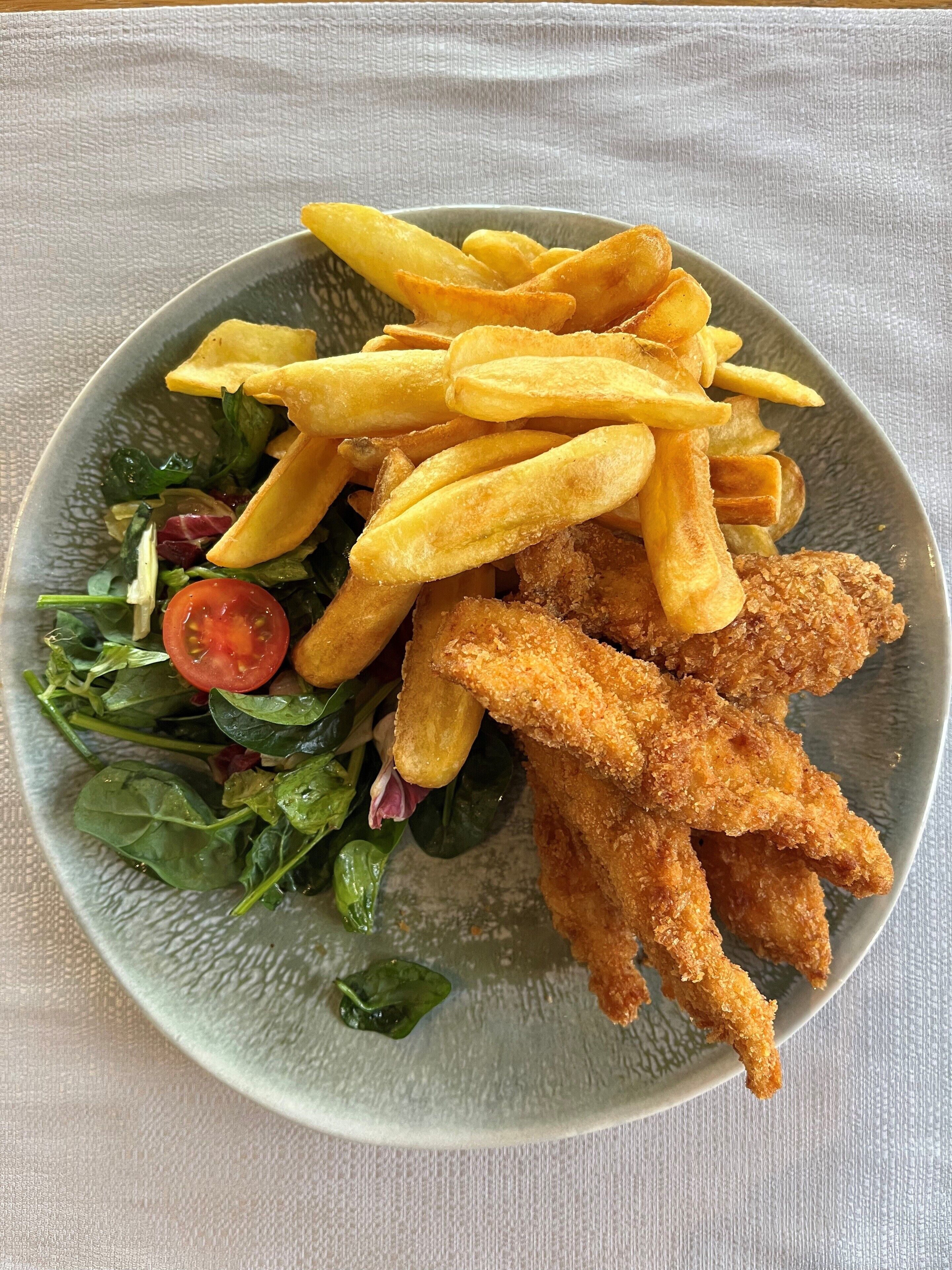 Um prato com salada, batatas fritas e peixe empanado.