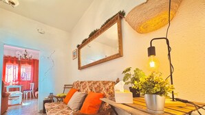 Uma sala de estar acolhedora com um sofá estampado com flores, uma mesa de centro de madeira, uma planta em vaso e um espelho pendurado.